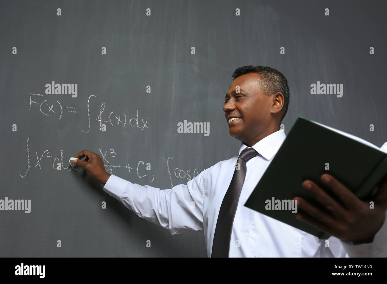 Confident Indian teacher writing math formulas on blackboard Stock ...