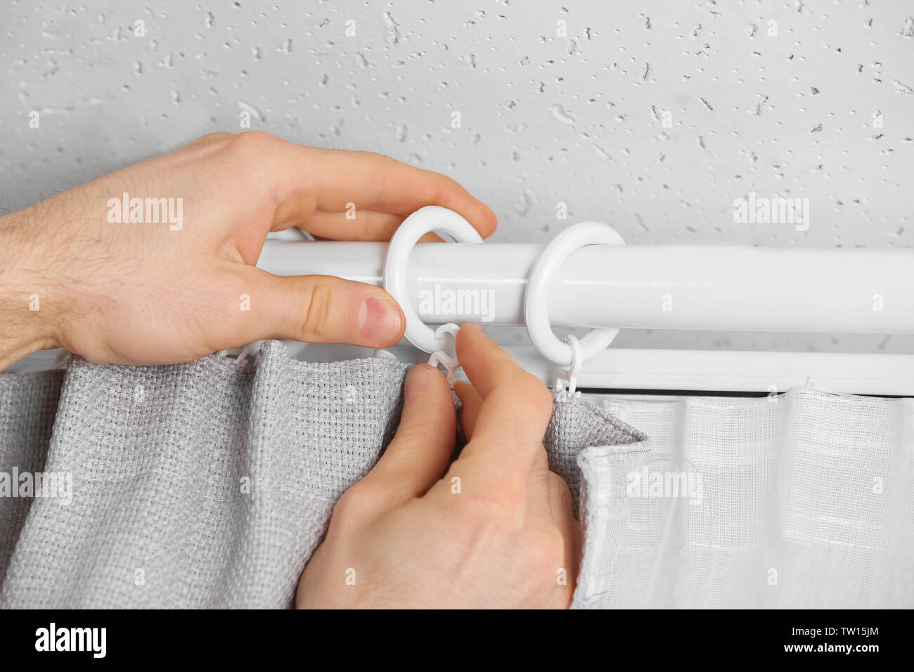 Male hands installing curtains over window Stock Photo - Alamy