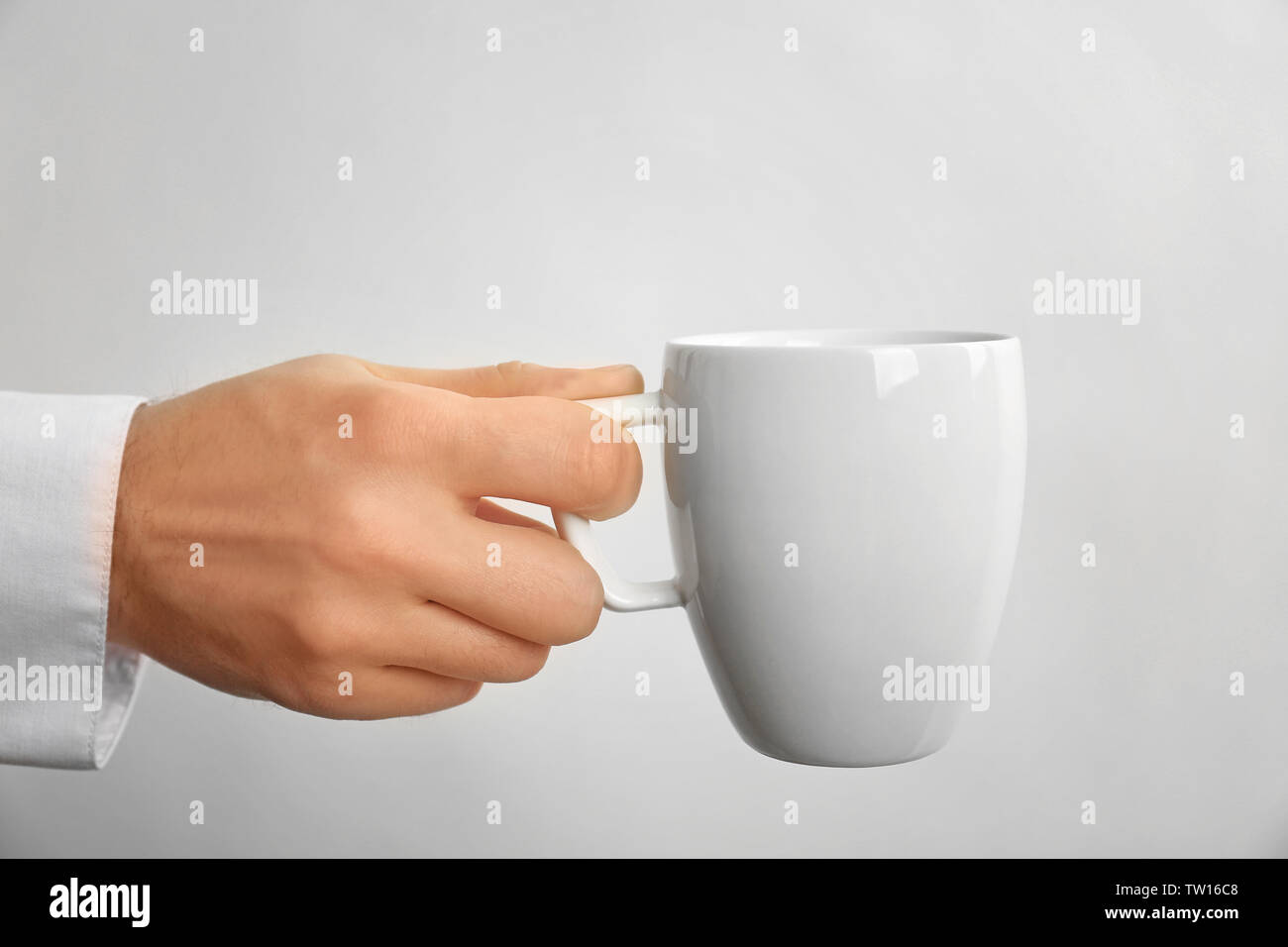 Male hand holding cup on white background Stock Photo - Alamy
