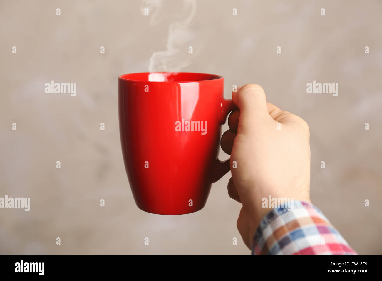 Male hand holding red cup on blurred background Stock Photo - Alamy