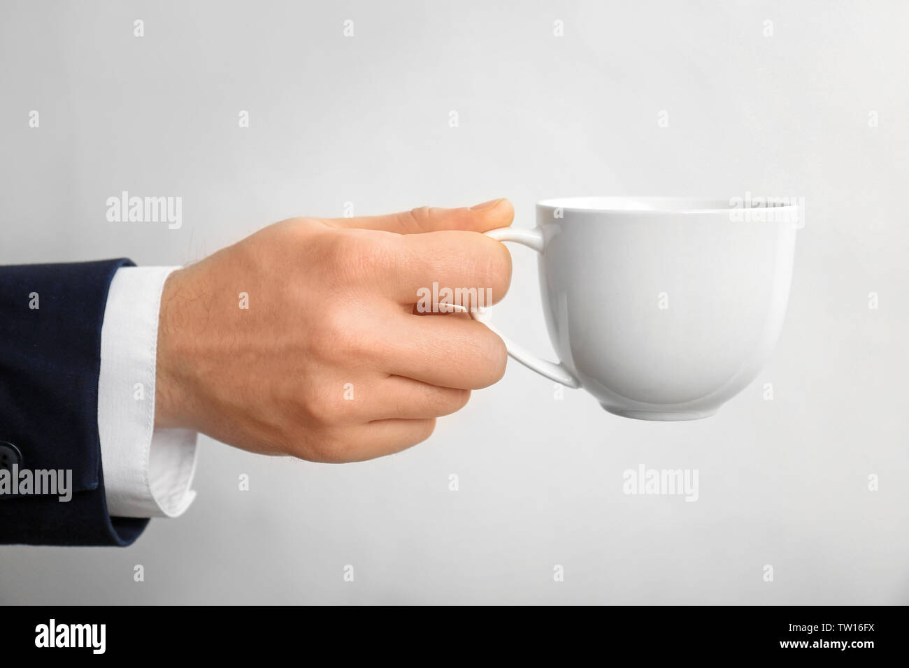 Male hand holding cup on white background Stock Photo - Alamy