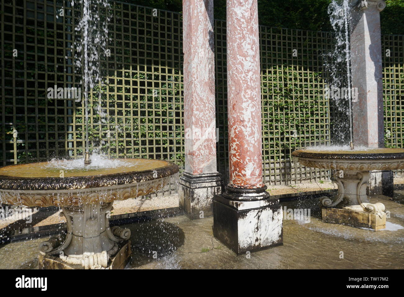 two water fountains spewing water up with marble columns and bowls in ...