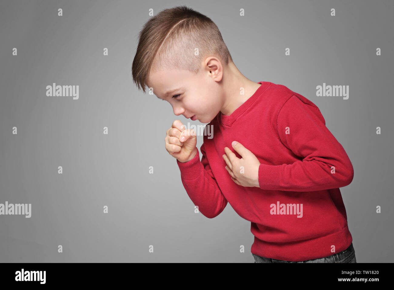 Cute little boy coughing on gray background Stock Photo - Alamy