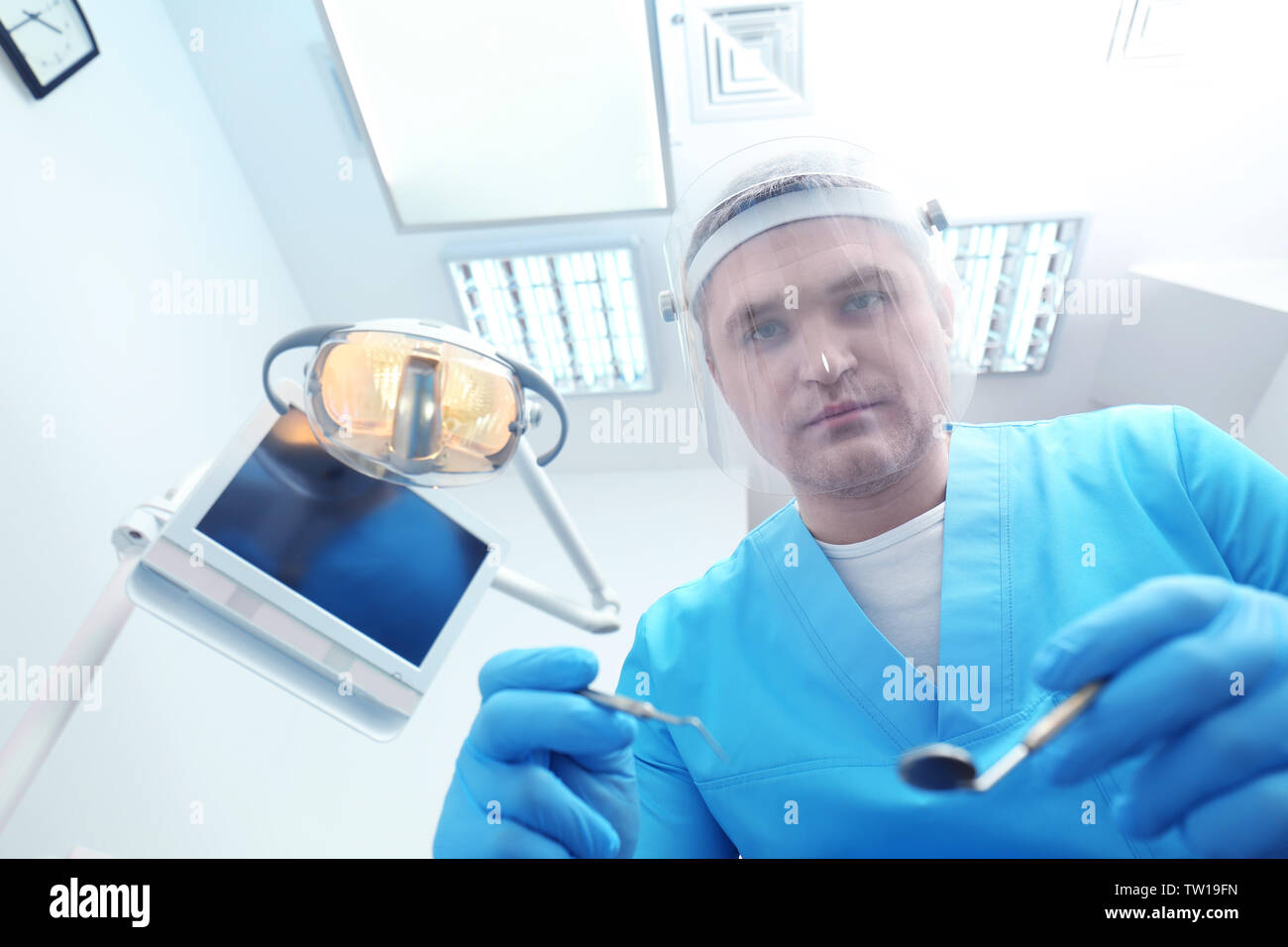 Dentist with mirror and periodontal explorer in clinic Stock Photo - Alamy