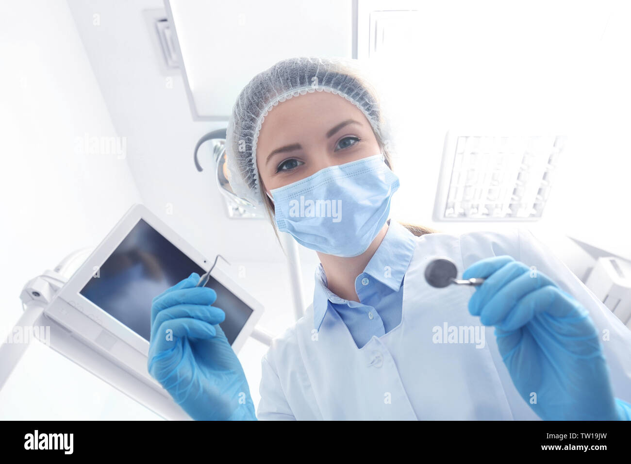 Dentist with mirror and periodontal explorer in clinic Stock Photo - Alamy