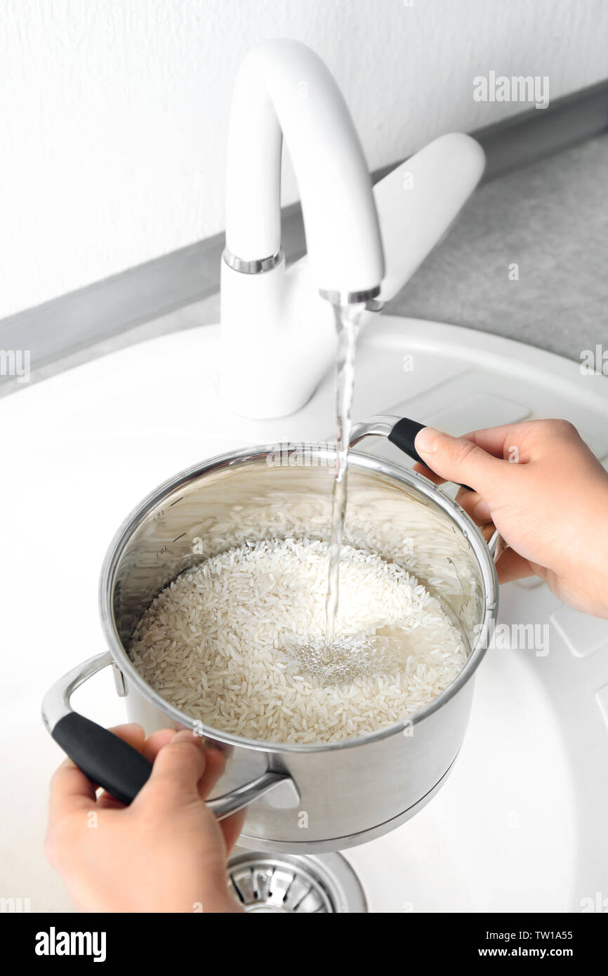 Woman rinsing rice in saucepan under running water Stock Photo - Alamy