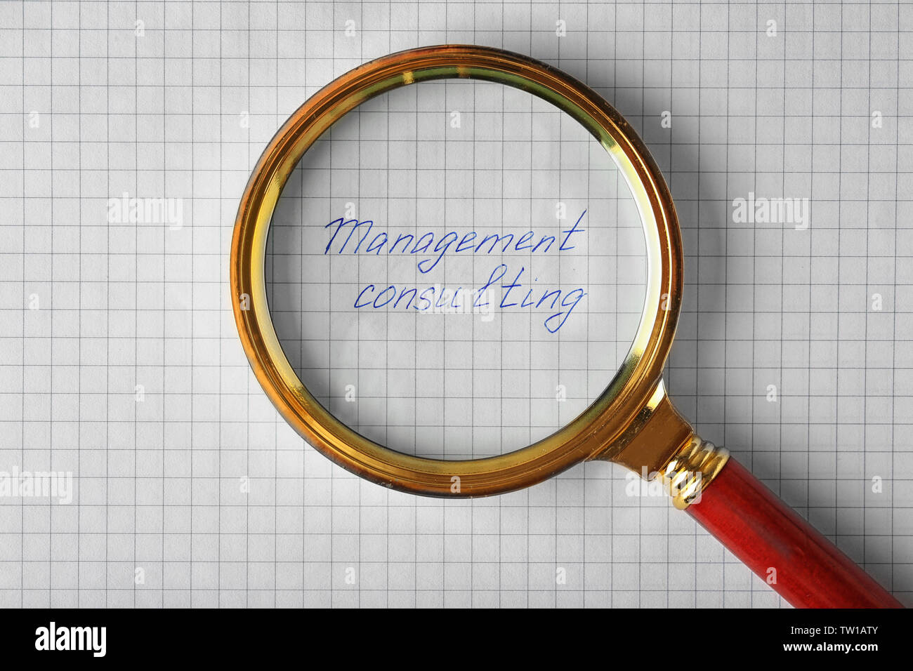 Text MANAGEMENT CONSULTING under magnifier on paper sheet background ...