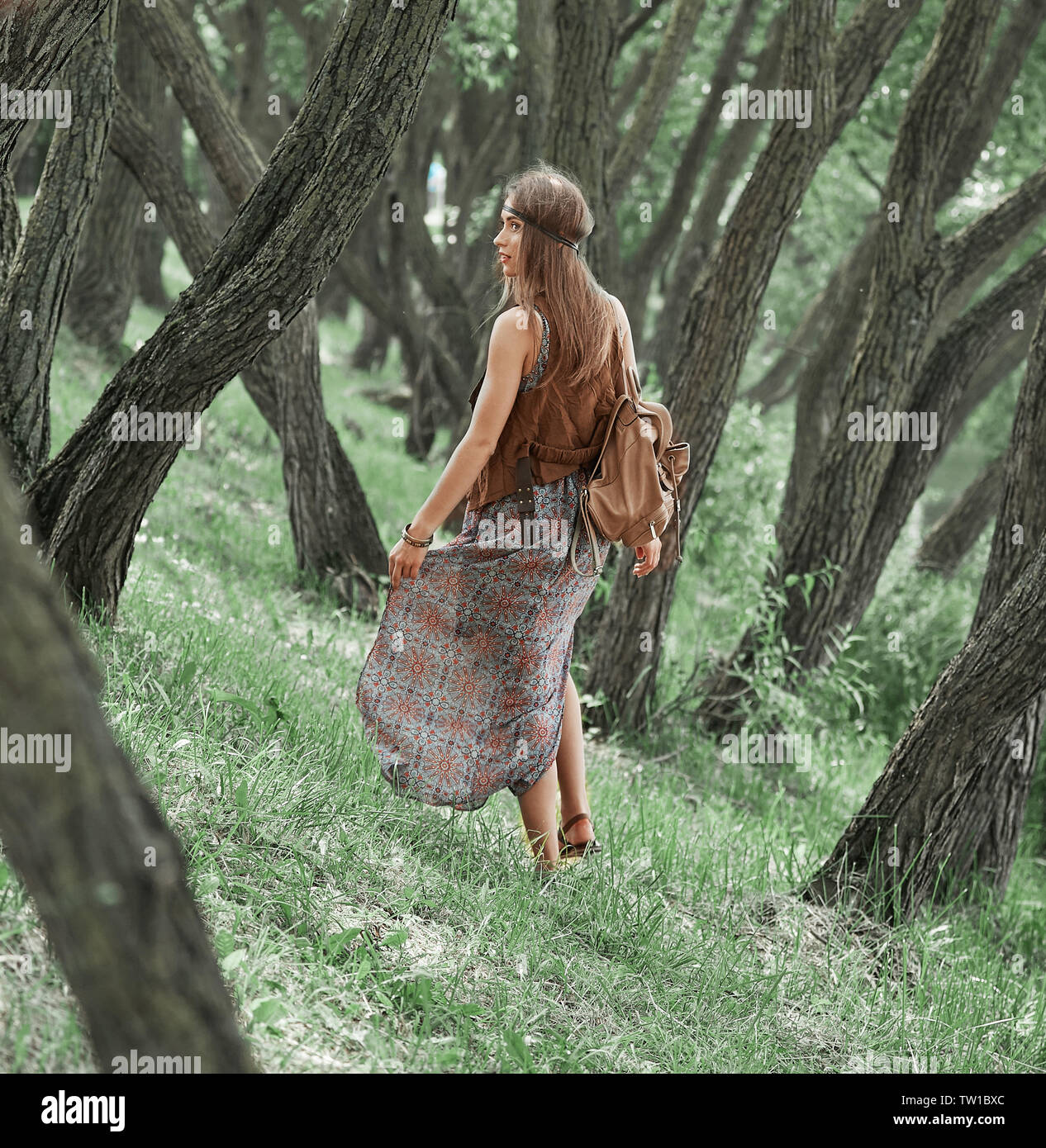 attractive hippie girl walking among the trees in the forest . the ...