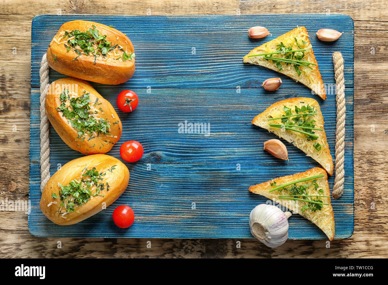 Tasty bread with grated cheese, garlic and herbs on cutting board Stock ...