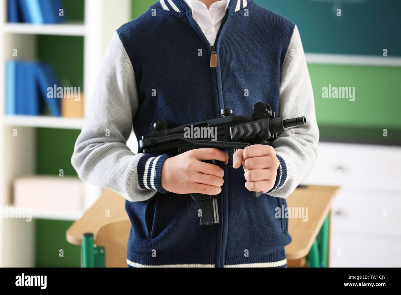Teenage boy with gun in classroom Stock Photo - Alamy