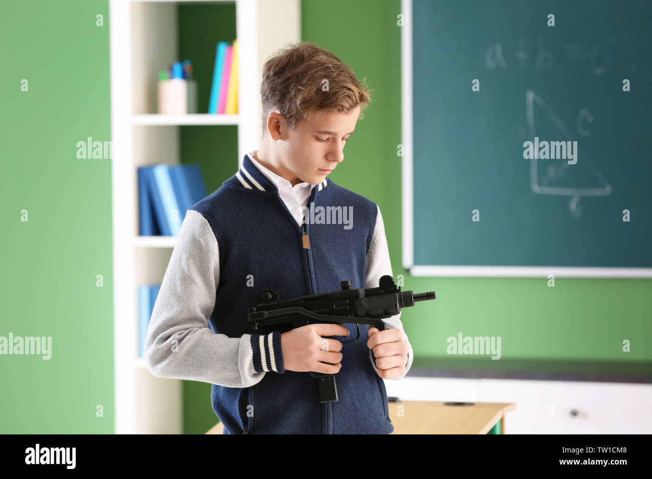 Teenage boy with gun in classroom Stock Photo - Alamy