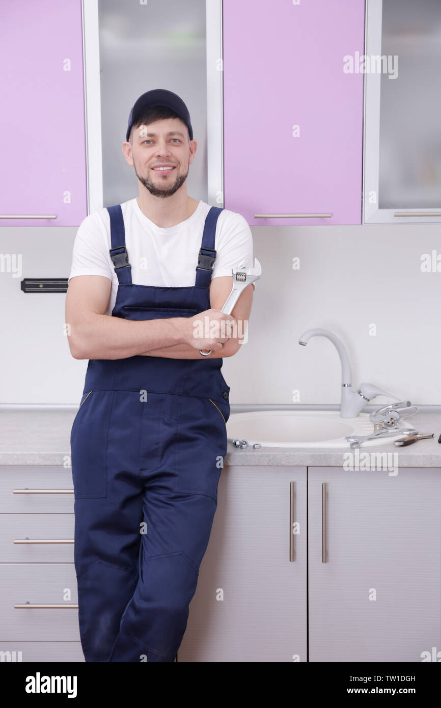 Plumber in blue uniform holding screw wrench at kitchen Stock Photo - Alamy