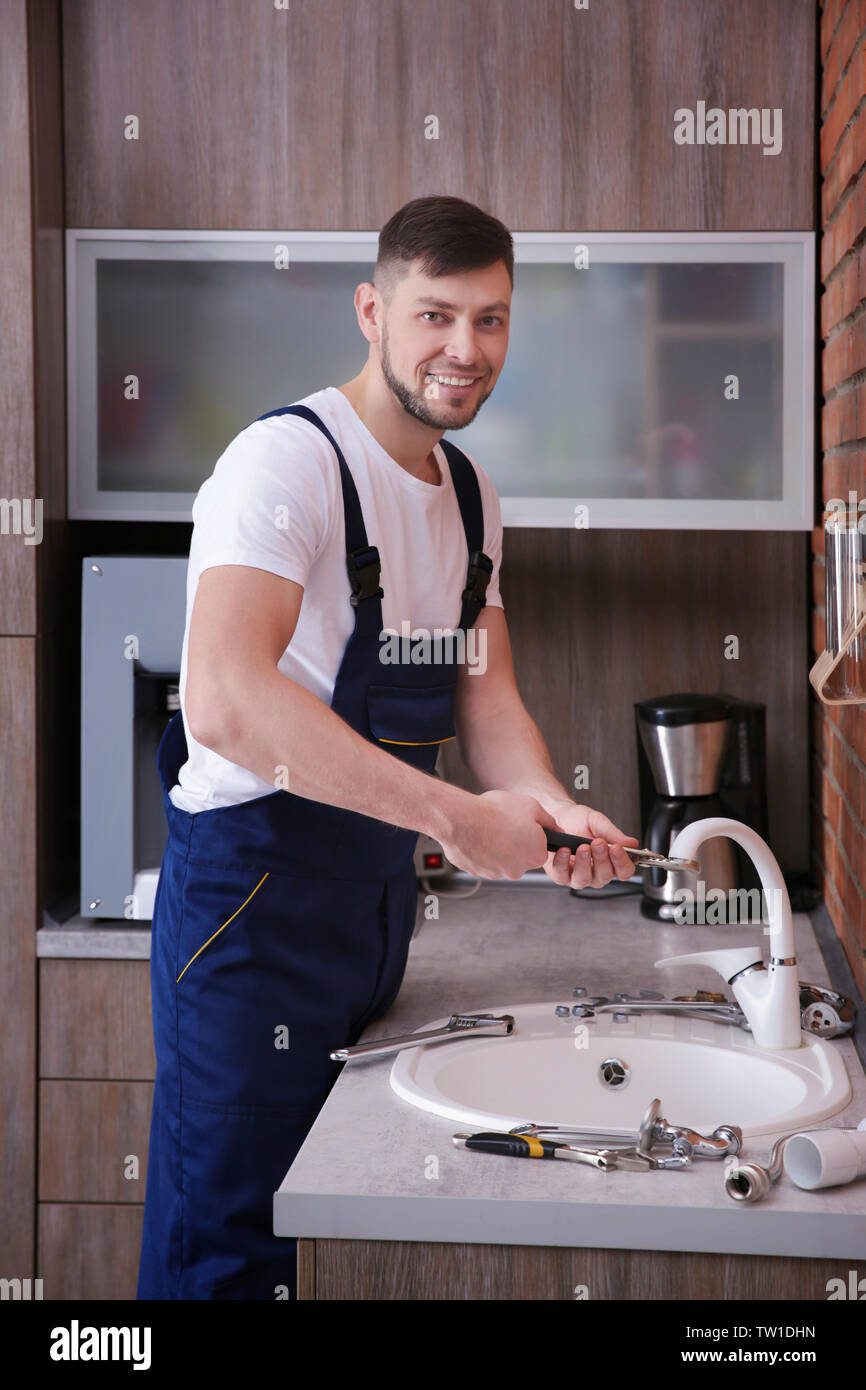 Plumber repairing faucet in kitchen Stock Photo - Alamy