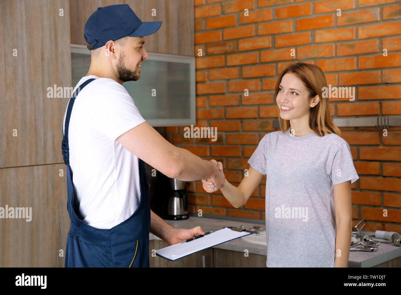 Plumber and woman shaking hands at home Stock Photo - Alamy