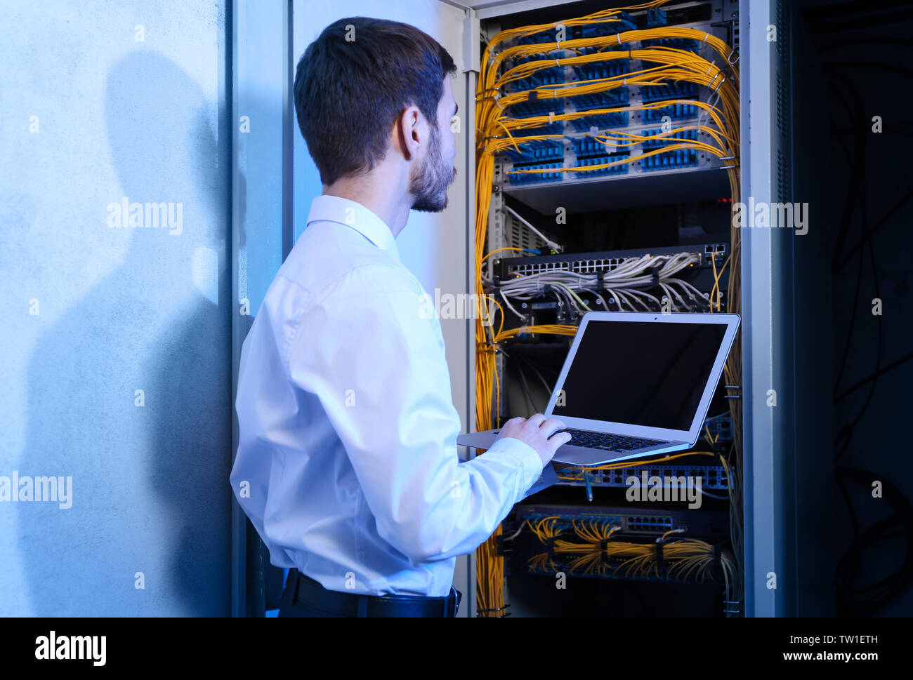 Handsome young engineer with laptop in server room Stock Photo - Alamy