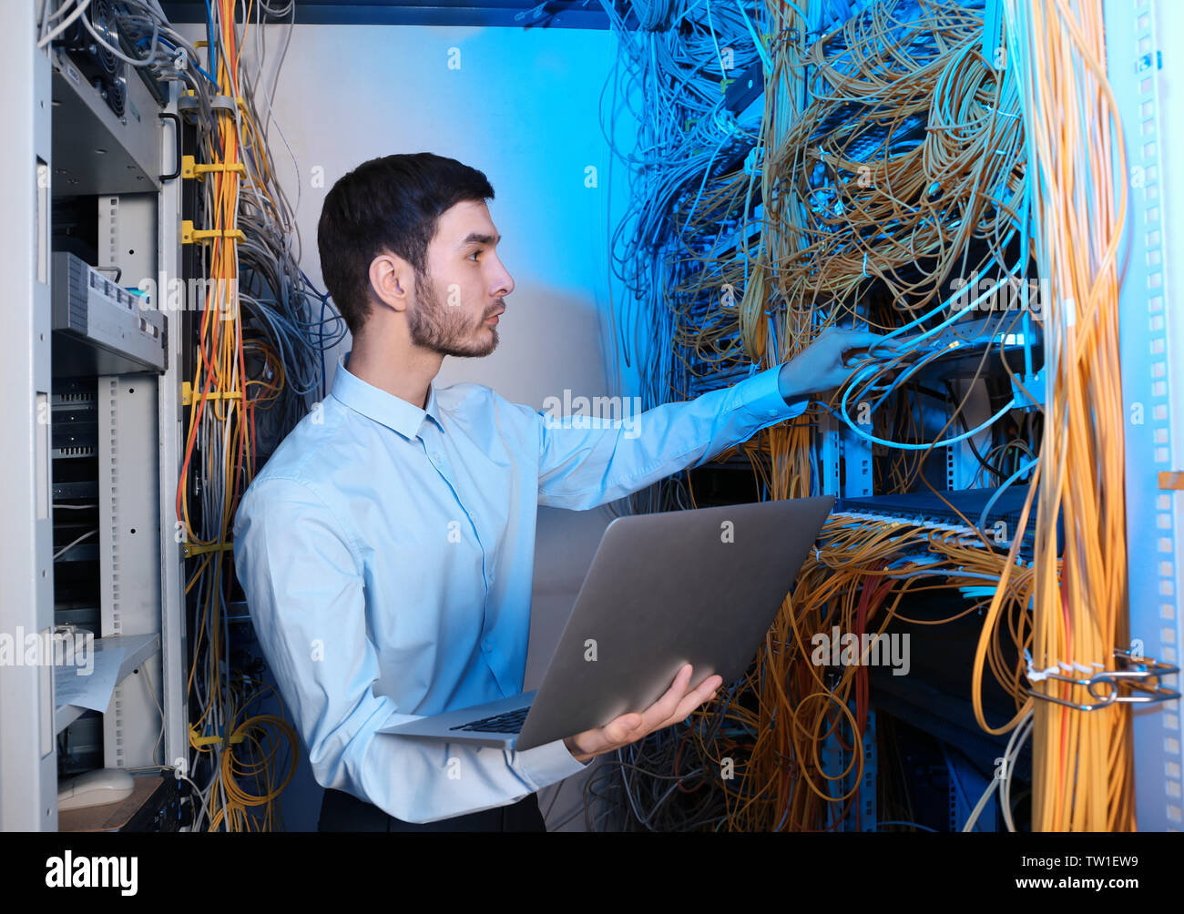 Handsome young engineer with laptop in server room Stock Photo - Alamy