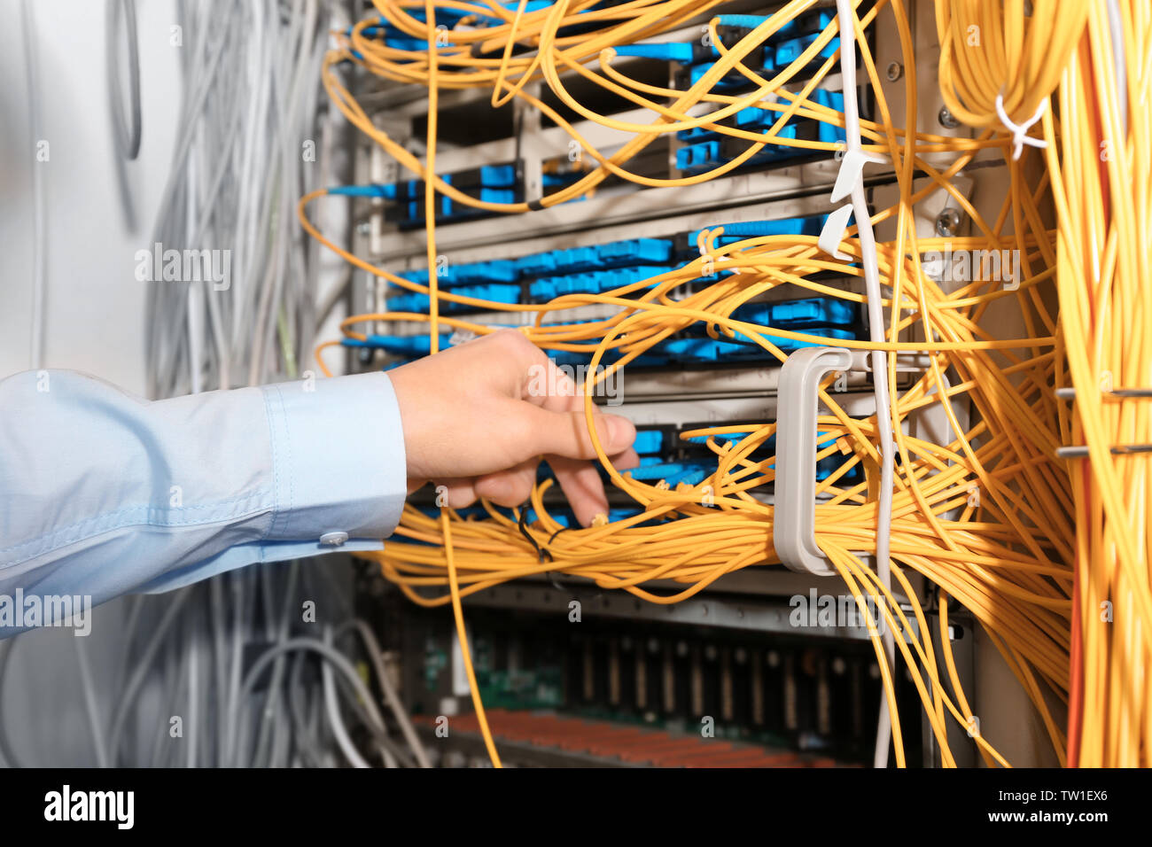 Hand of young engineer connecting cables in server room Stock Photo - Alamy