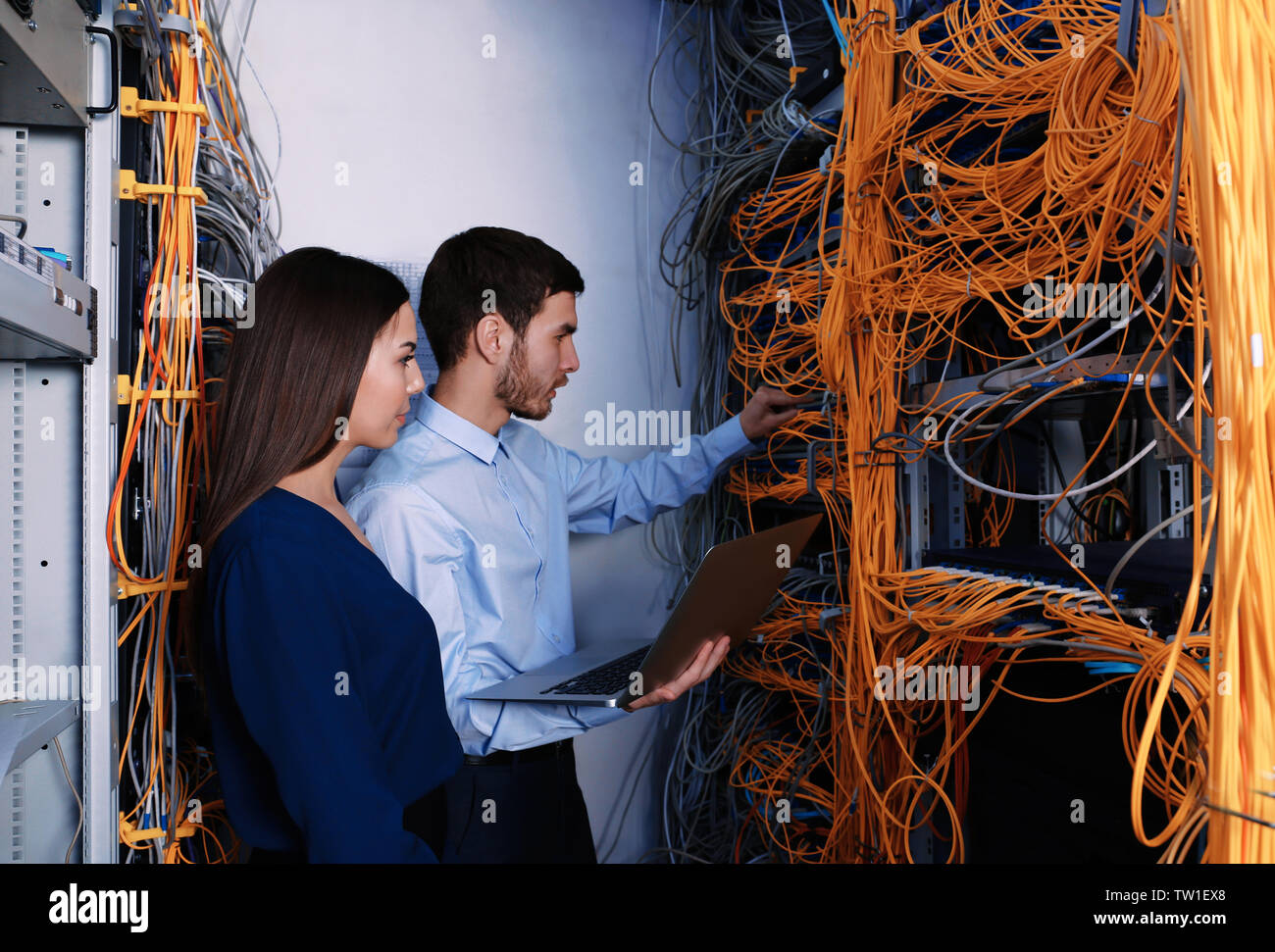 Young engineers connecting cables in server room Stock Photo - Alamy