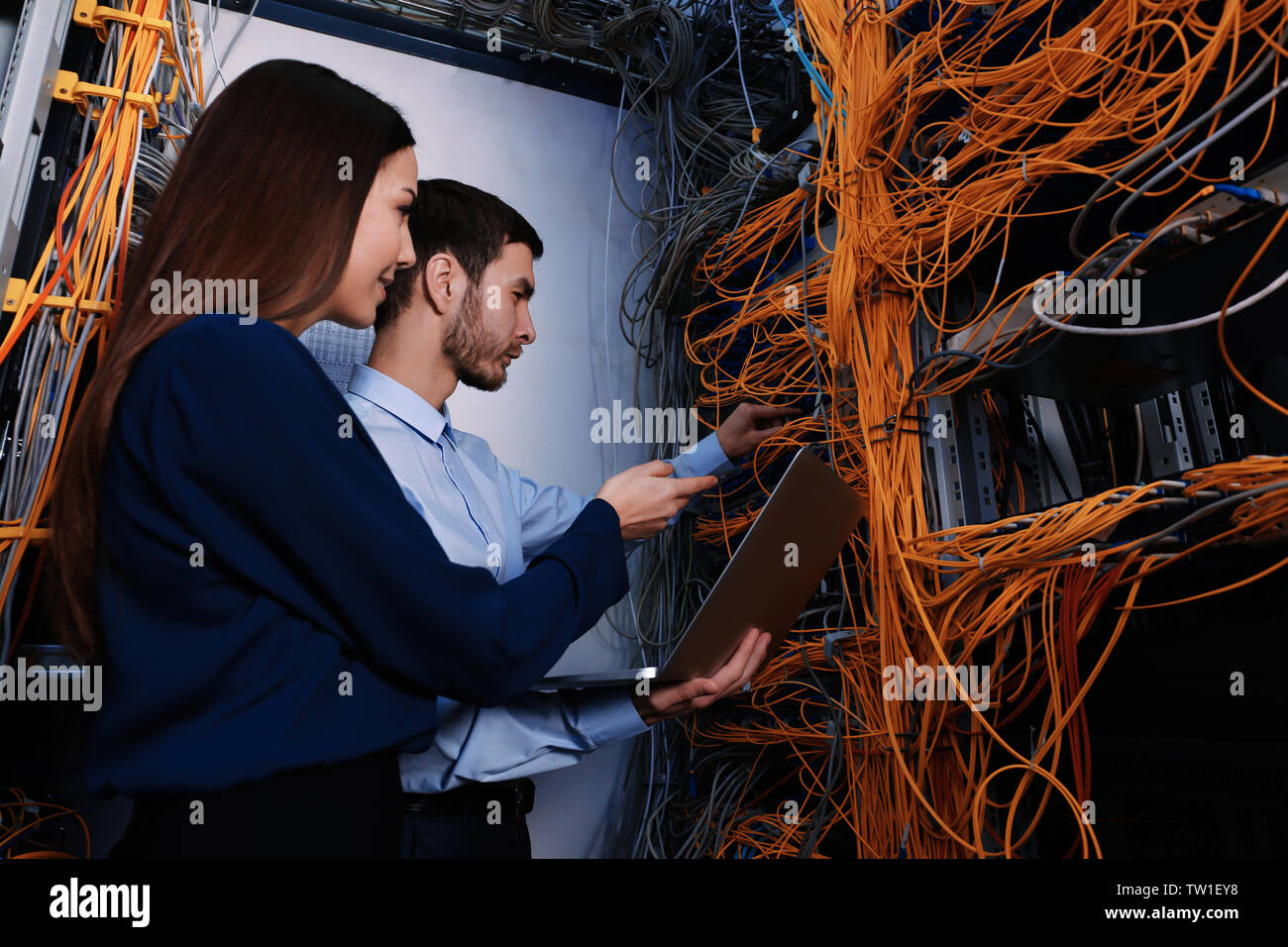 Young engineers connecting cables in server room Stock Photo - Alamy