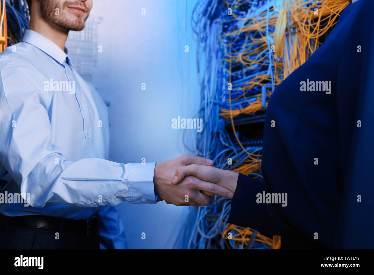Young engineers shaking hands in server room Stock Photo - Alamy
