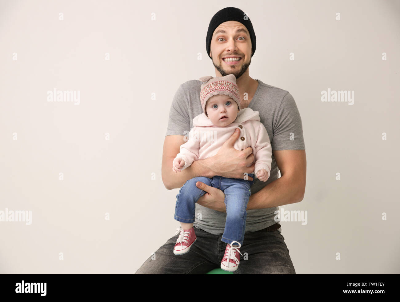 Father posing with cute baby daughter on light background Stock Photo ...