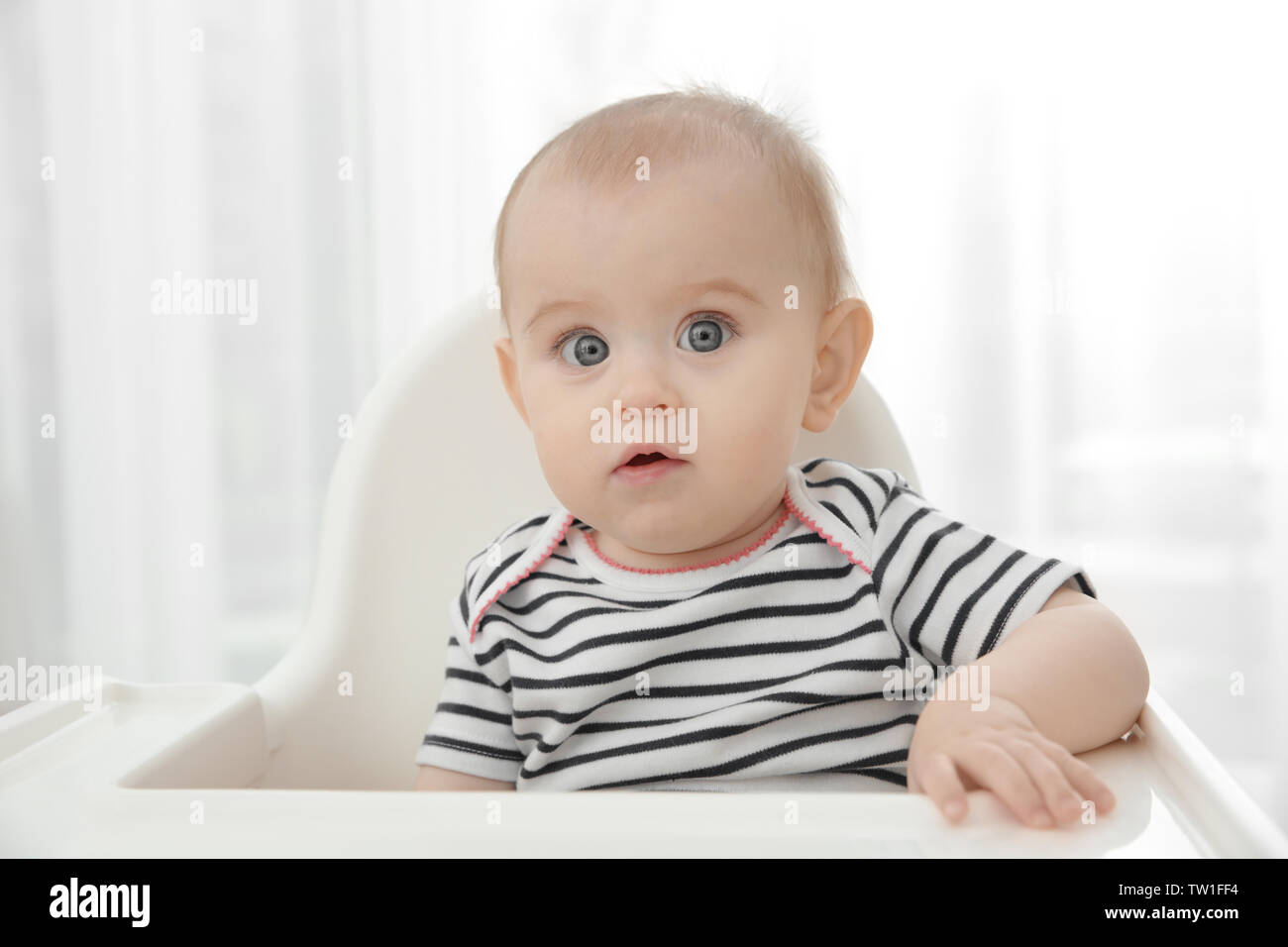 Adorable baby girl sitting in chair for babies Stock Photo - Alamy