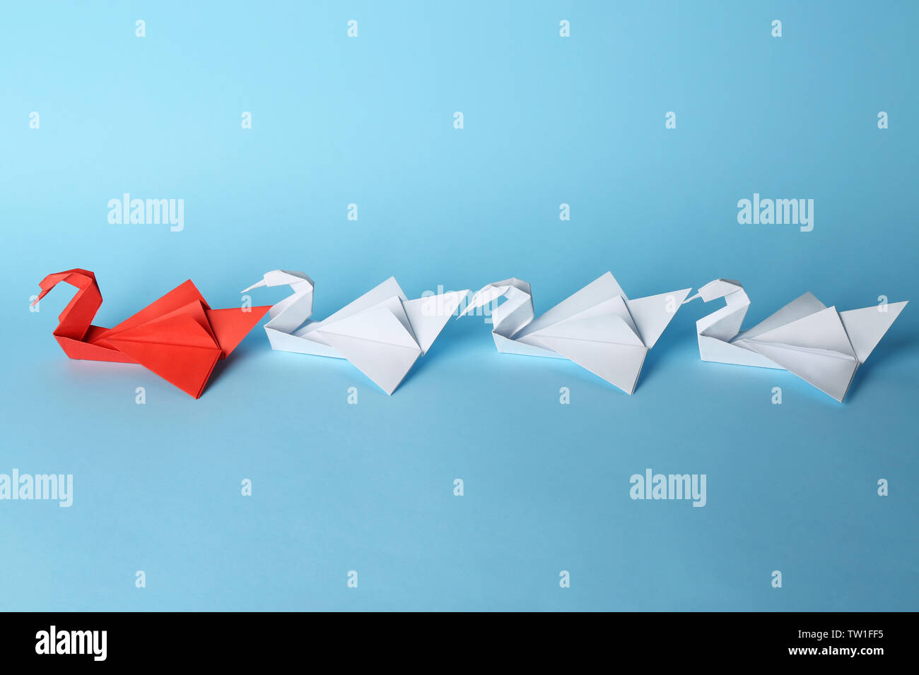 Boss vs Leader concept. White origami birds behind red one on blue ...