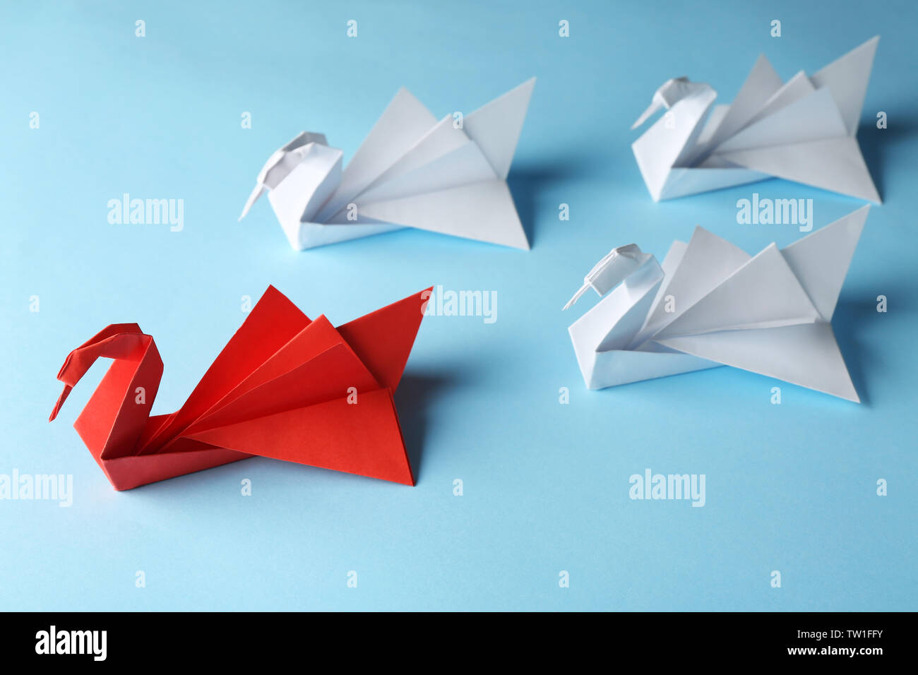 Boss vs Leader concept. White origami birds behind red one on blue ...