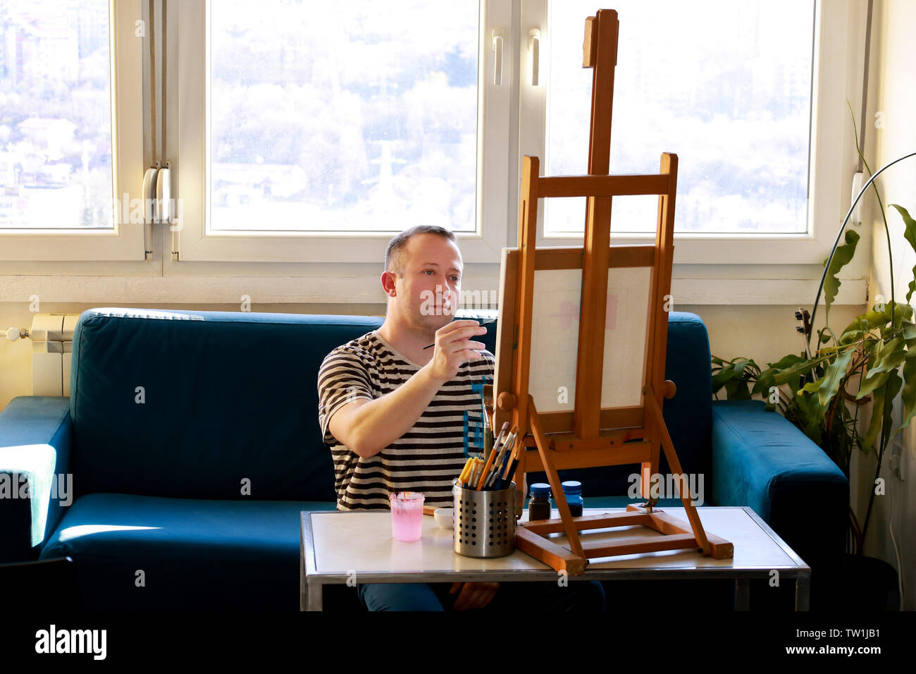Male artist painter working in workshop with canvas on wood drawing ...
