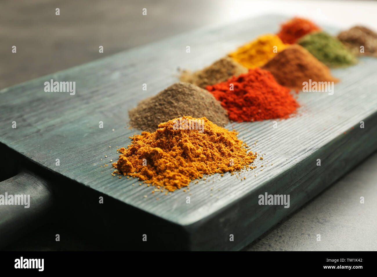 Wooden board with heaps of various powder spices on table Stock Photo ...