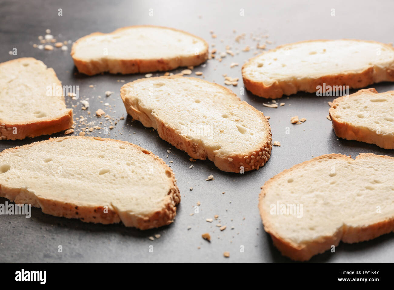 Slices and crumbs of wheaten bread with sesame seeds on grey background ...