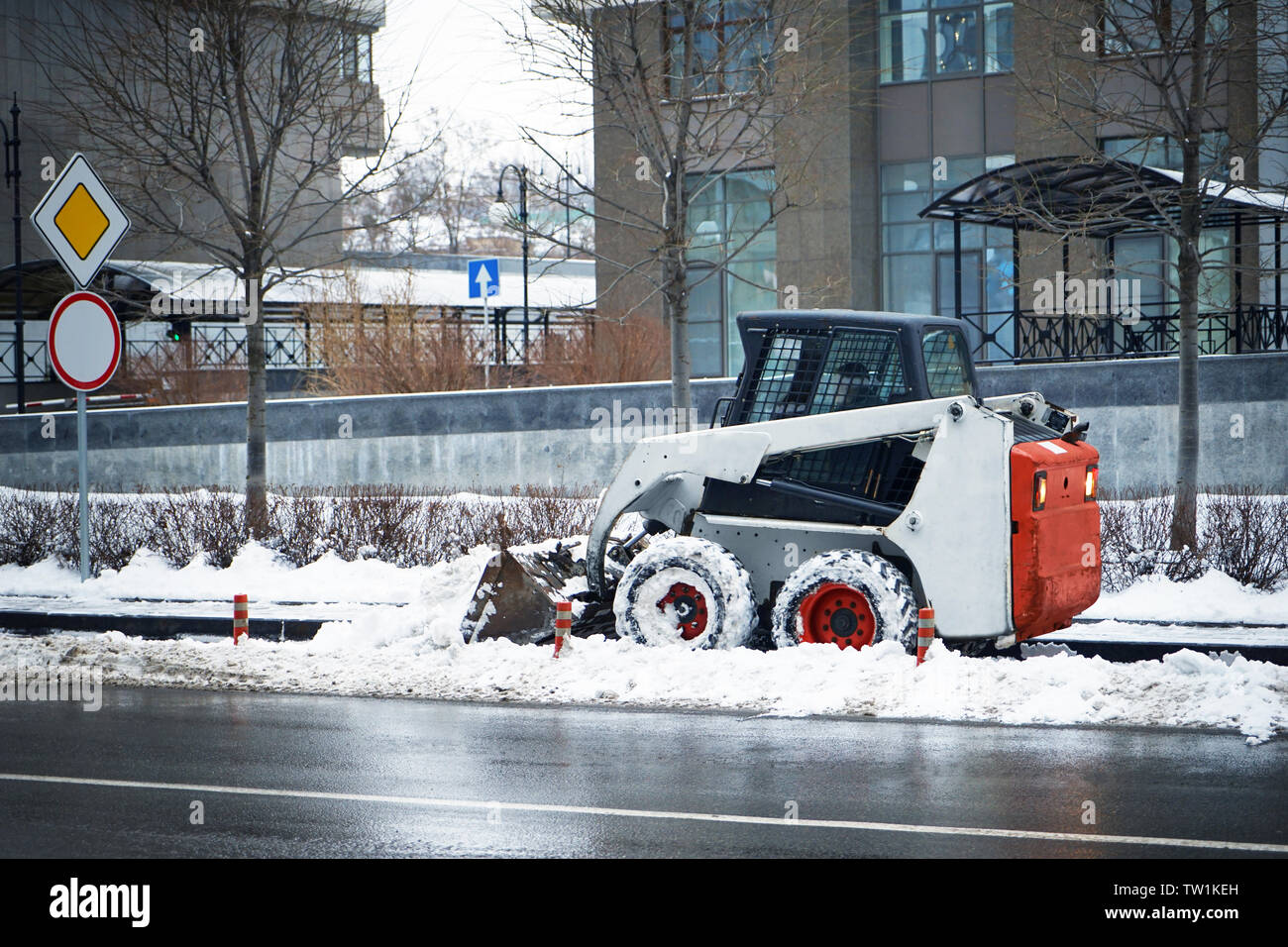 Snow plow cleaning street in town Stock Photo - Alamy