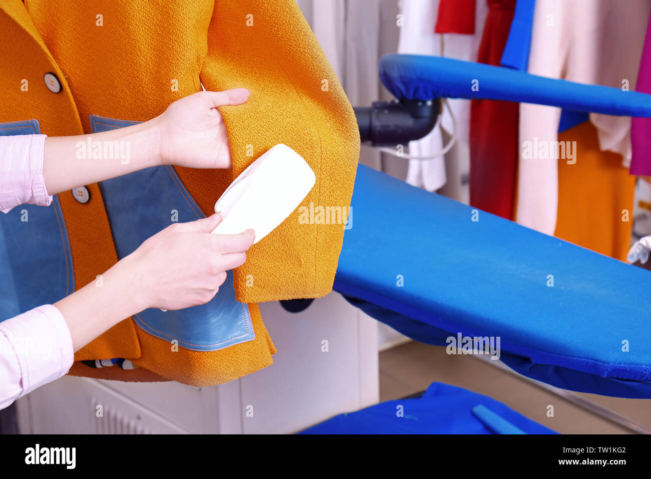 Female laundry worker cleaning coat with brush for clothes, closeup ...