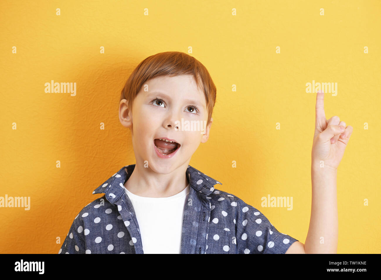 Cute little boy with index finger up on color background Stock Photo ...