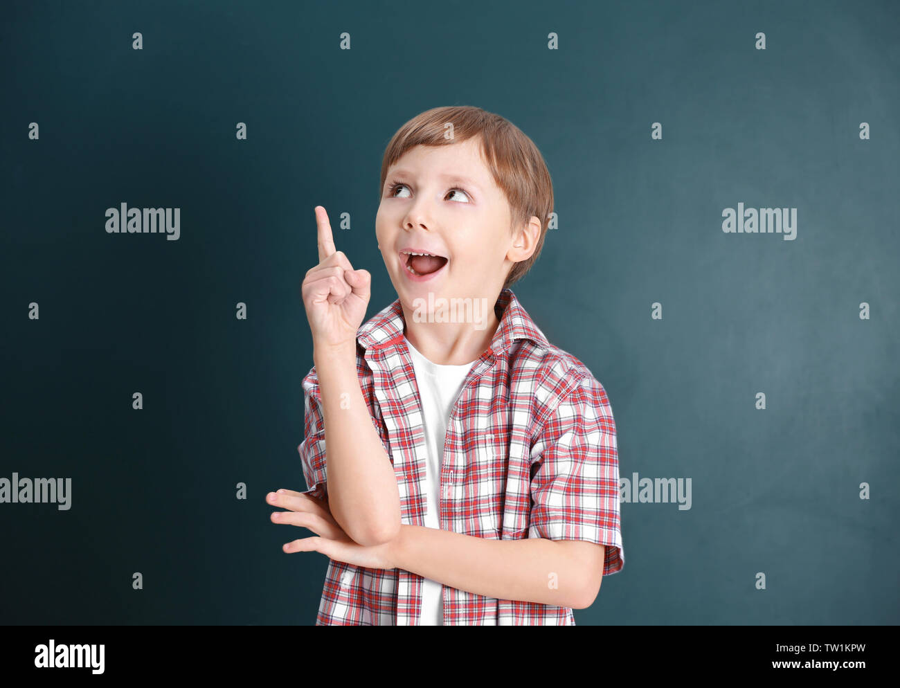 Cute little boy with index finger up on school blackboard background ...