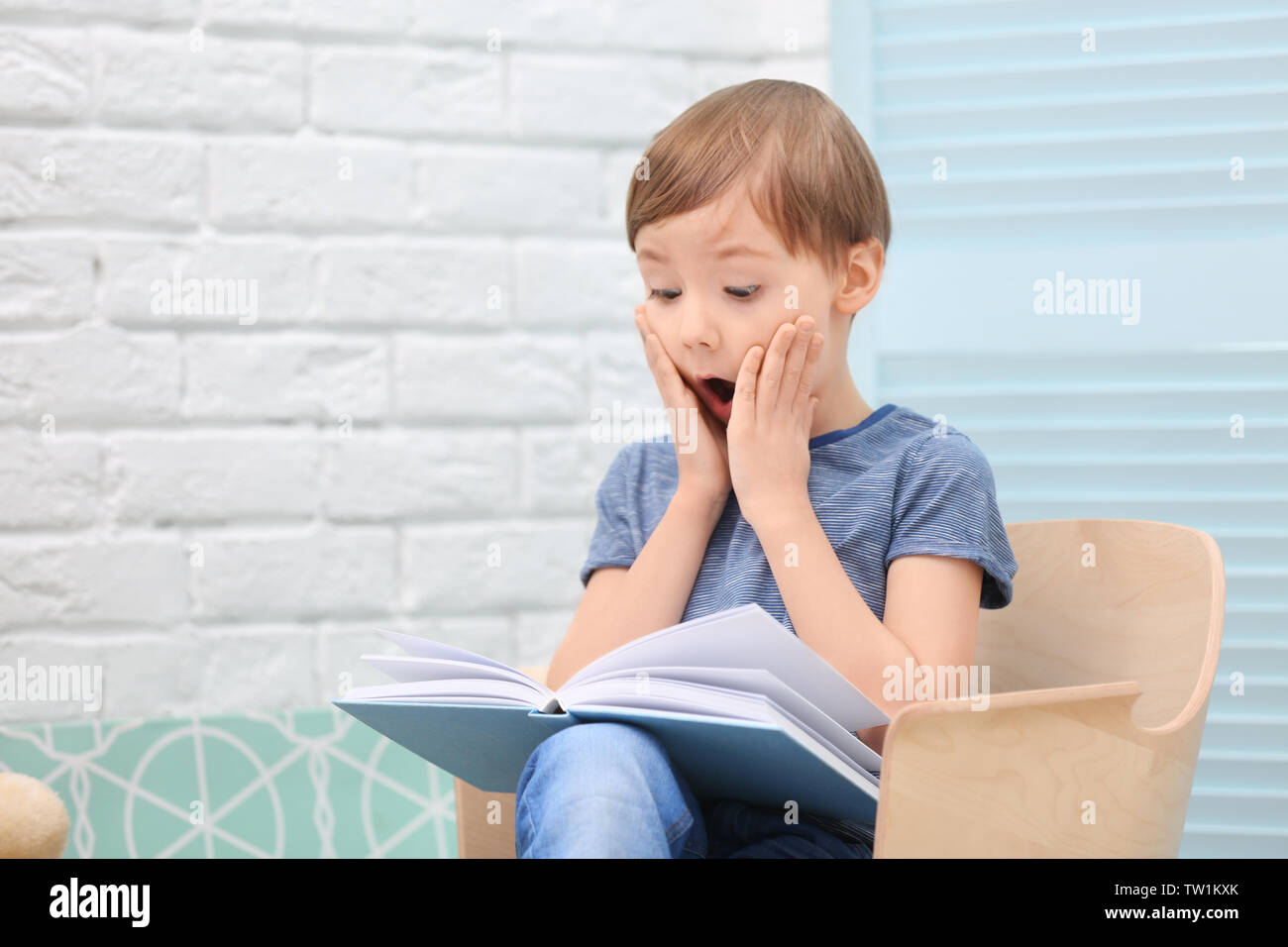 Cute little boy reading book at home Stock Photo - Alamy