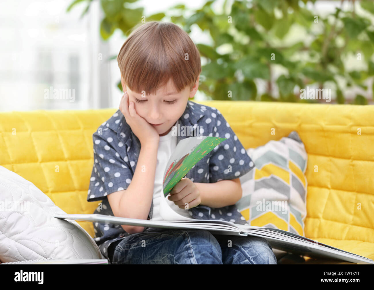 Cute little boy reading book at home Stock Photo - Alamy