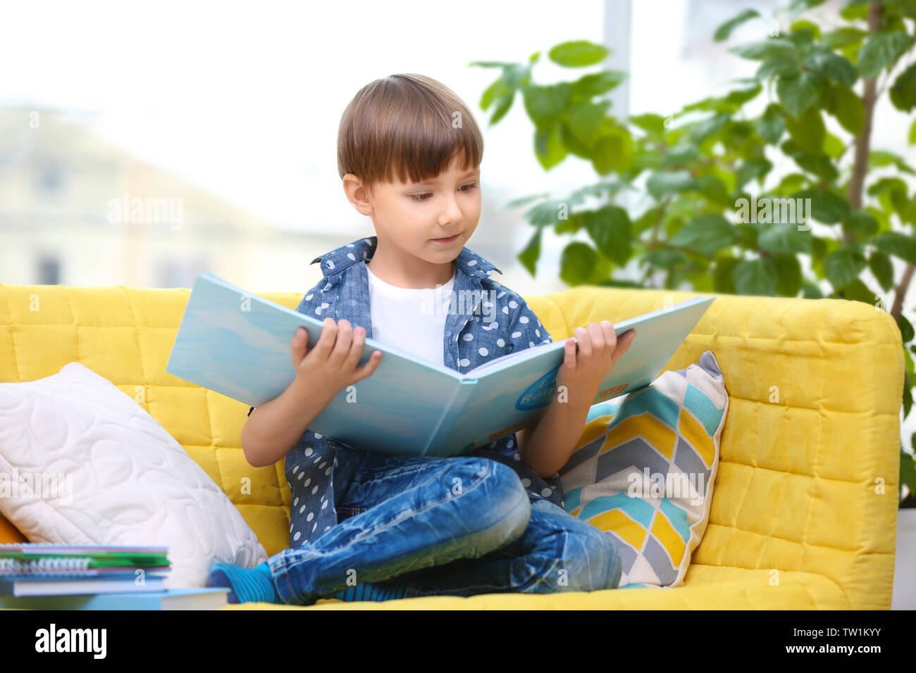Cute little boy reading book at home Stock Photo - Alamy