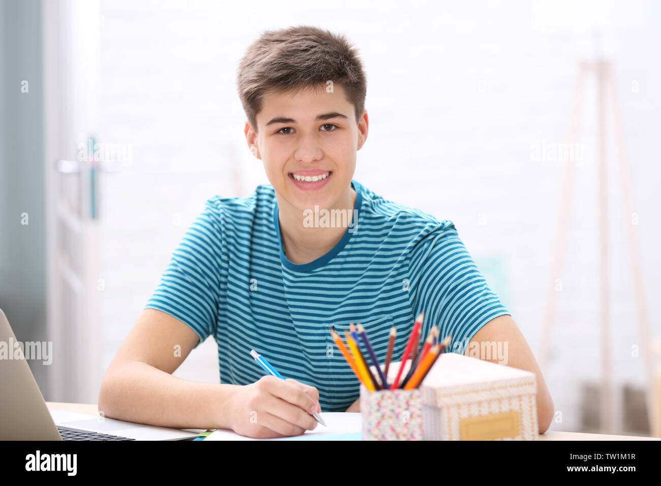 Teenager sitting at table and taking notes at home Stock Photo - Alamy