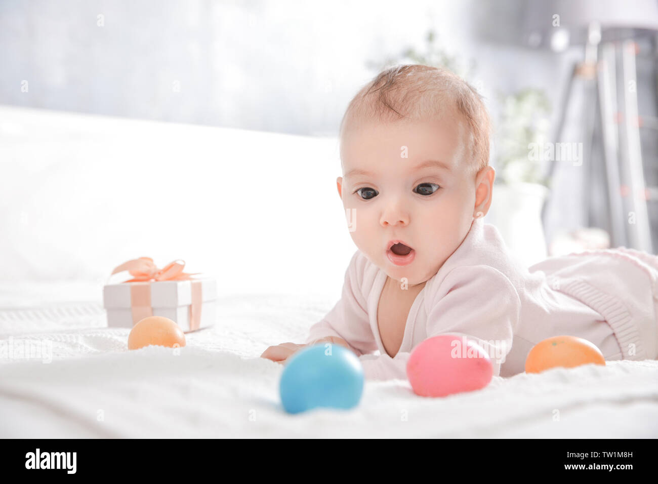 Cute little baby with Easter eggs lying on bed at home Stock Photo - Alamy