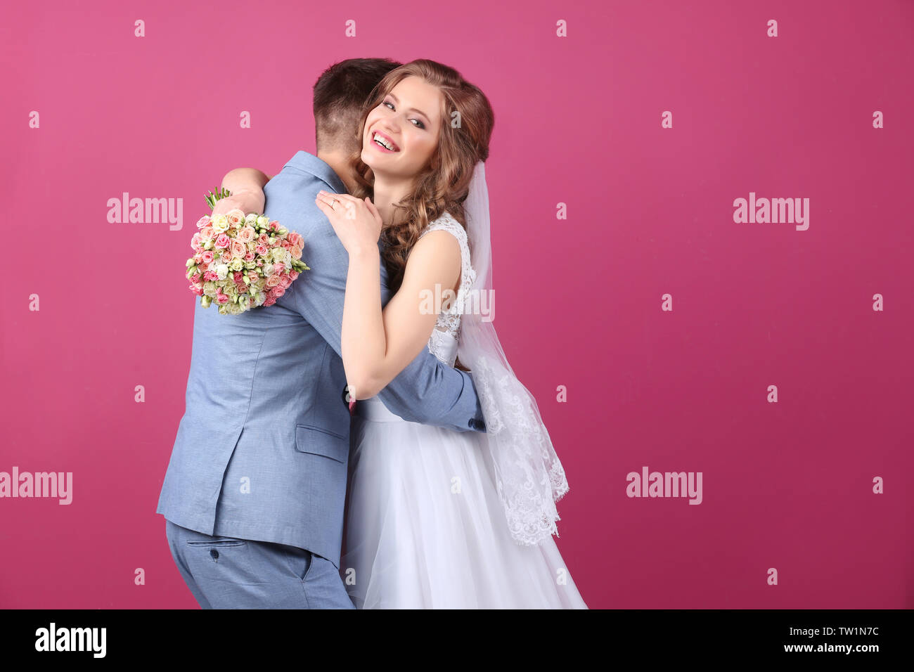 Happy wedding couple dancing on color background Stock Photo - Alamy