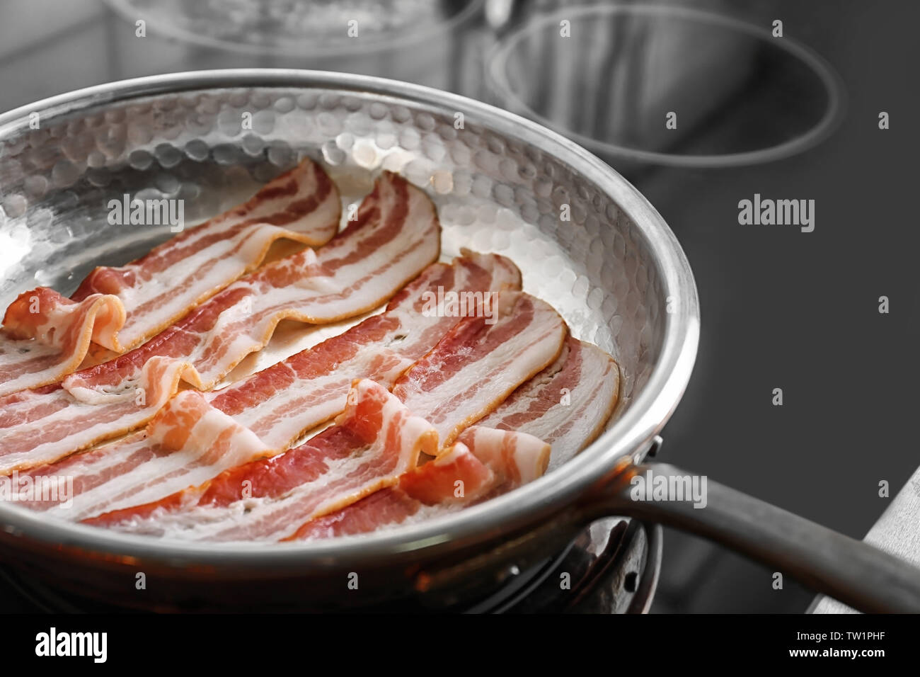 Pan with strips of bacon on stove Stock Photo - Alamy