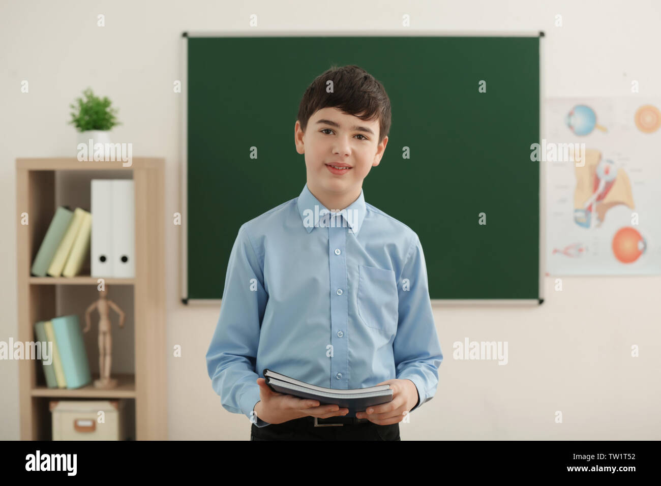 Cute boy standing in classroom Stock Photo - Alamy