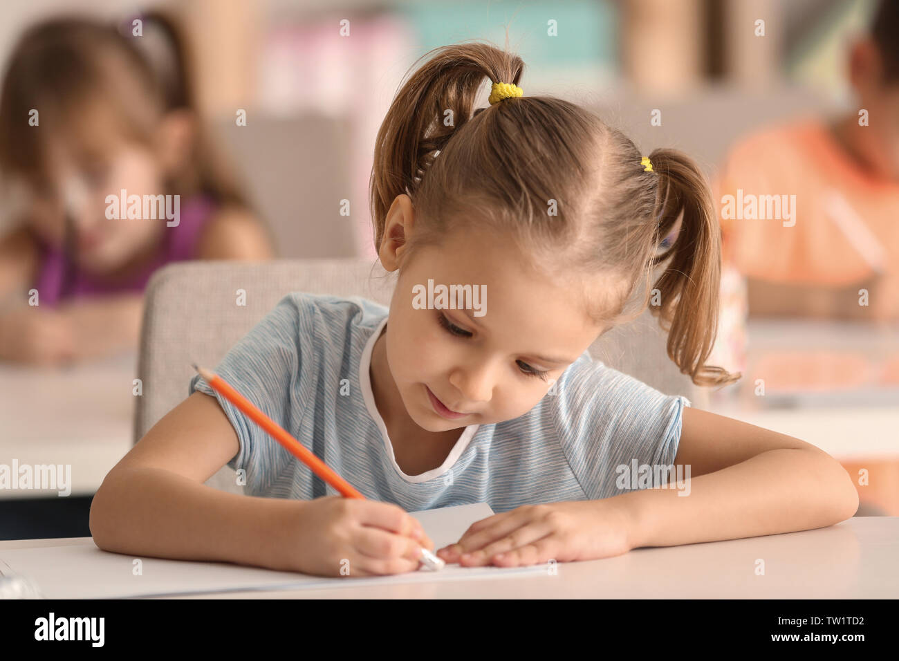 Cute girl drawing in classroom Stock Photo - Alamy