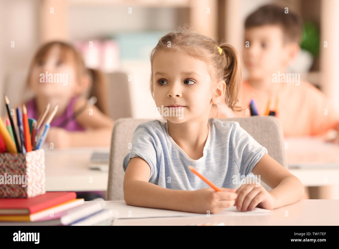 Cute girl drawing in classroom Stock Photo - Alamy