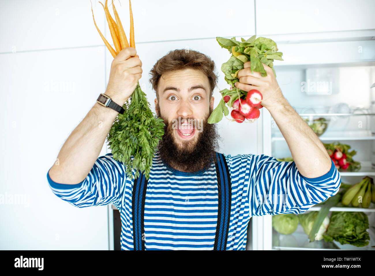 Portrait of a well-looking man with carrot and radish in front of the ...