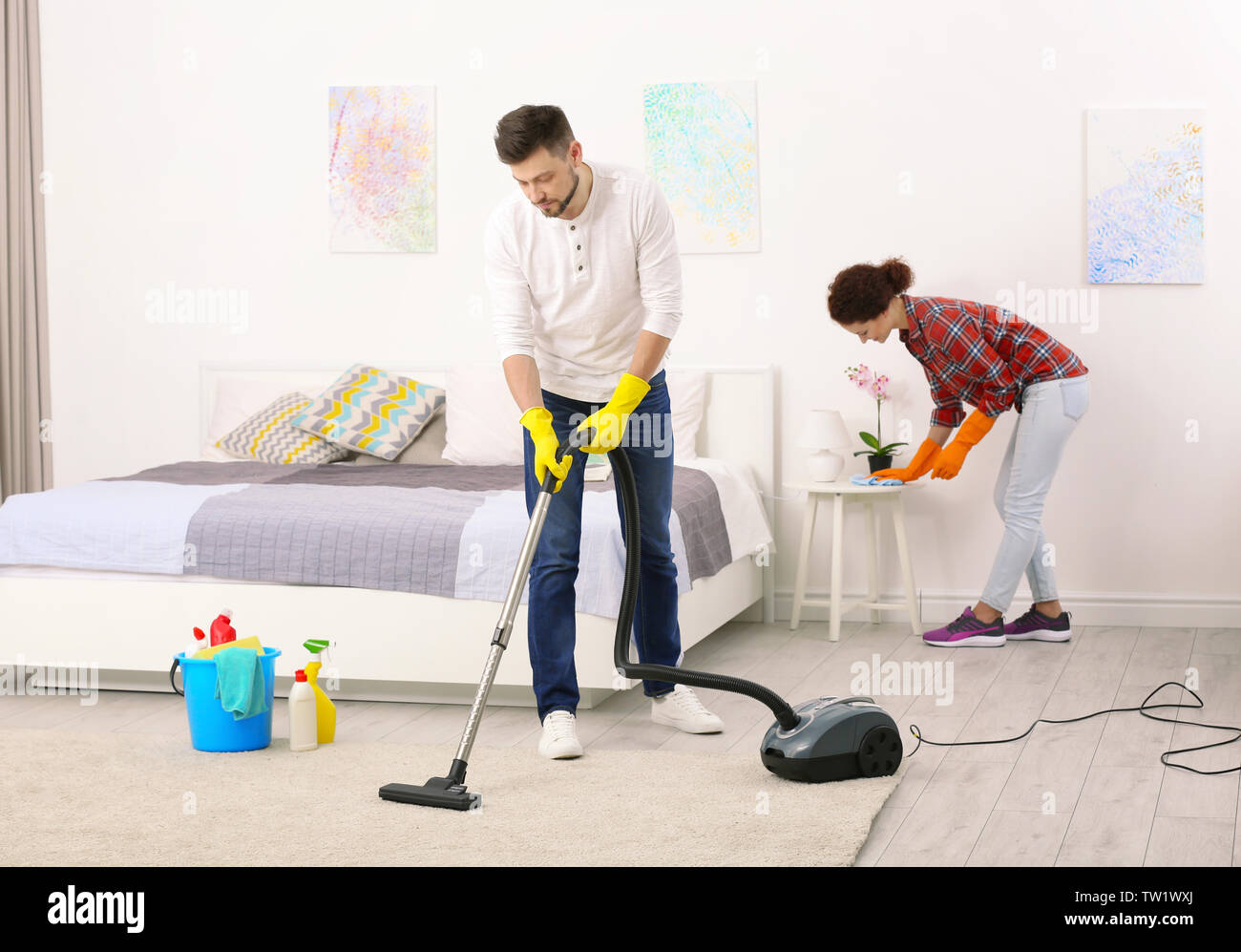 Happy young couple cleaning home together Stock Photo - Alamy