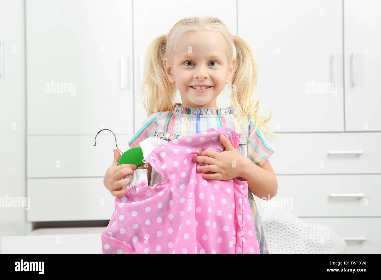 Cute small girl with clothes in wardrobe Stock Photo - Alamy