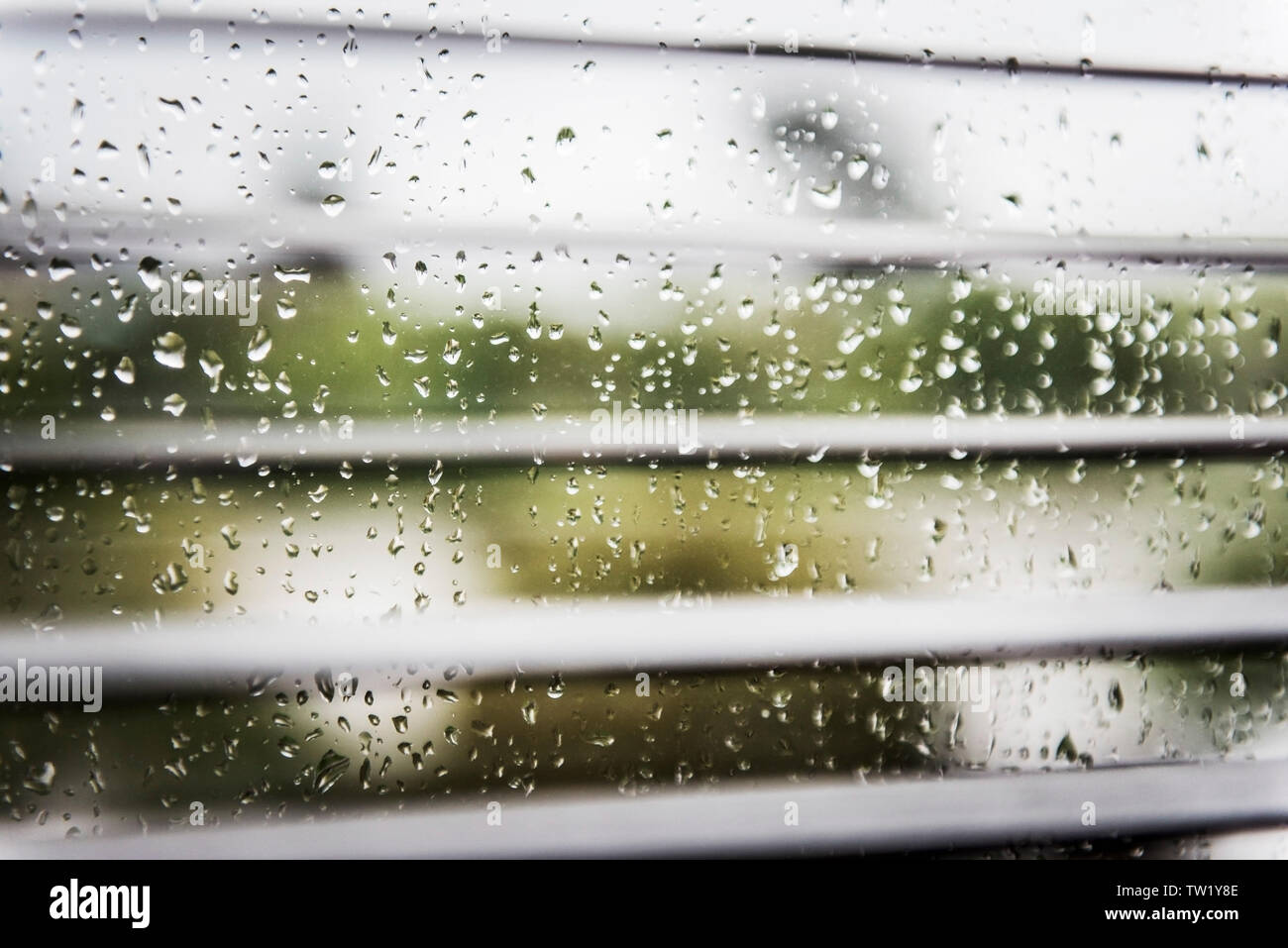 Raindrops on a window pane seen through blinds Stock Photo - Alamy