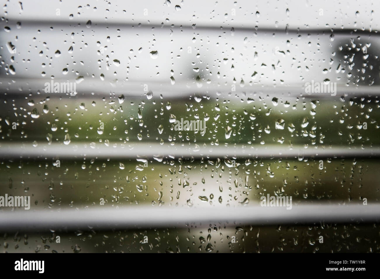 Raindrops on a window pane seen through blinds Stock Photo - Alamy
